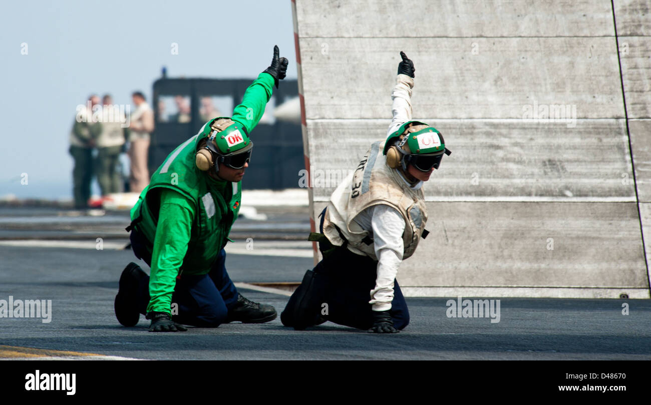 Sailors aboard a U.S. Navy aircraft carrier signal for an aircraft ...