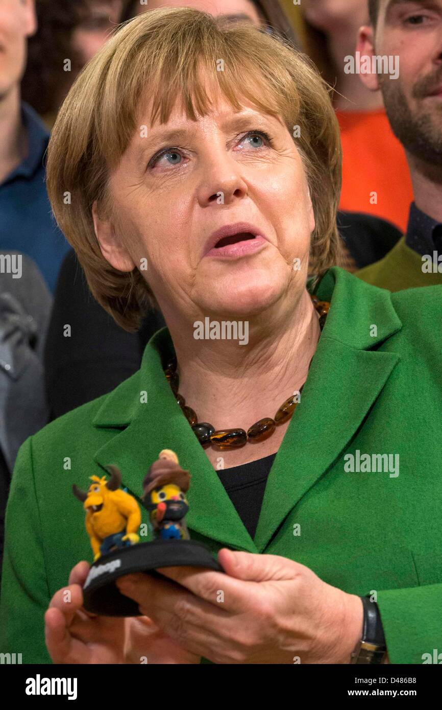 German Chancellor Angela Merkel holds models of characters from a Wooga ...