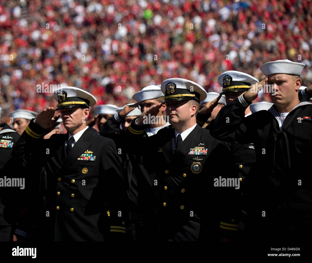 Sailors aboard a U.S. Navy vessel salute during the national anthem ...