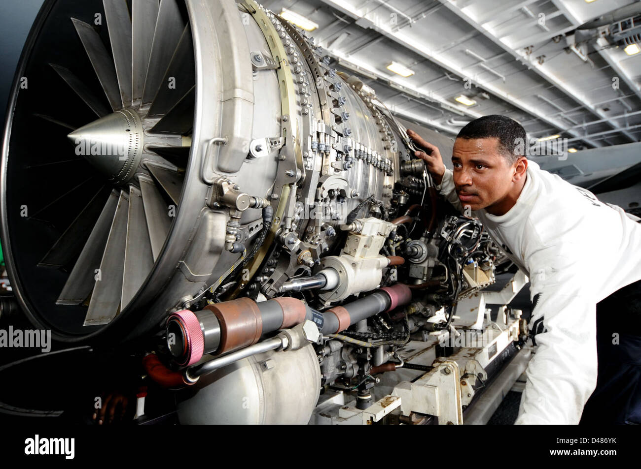 A U.S. Navy Sailor moves an aircraft engine aboard a Navy vessel as ...