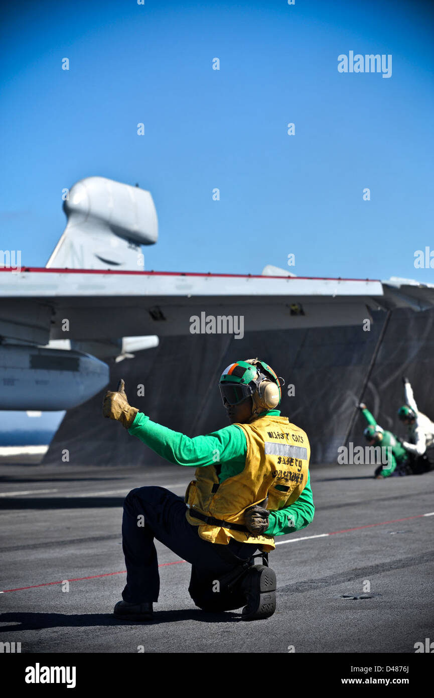 A Sailor aboard a U.S. Navy ship signals for the launch of an aircraft ...