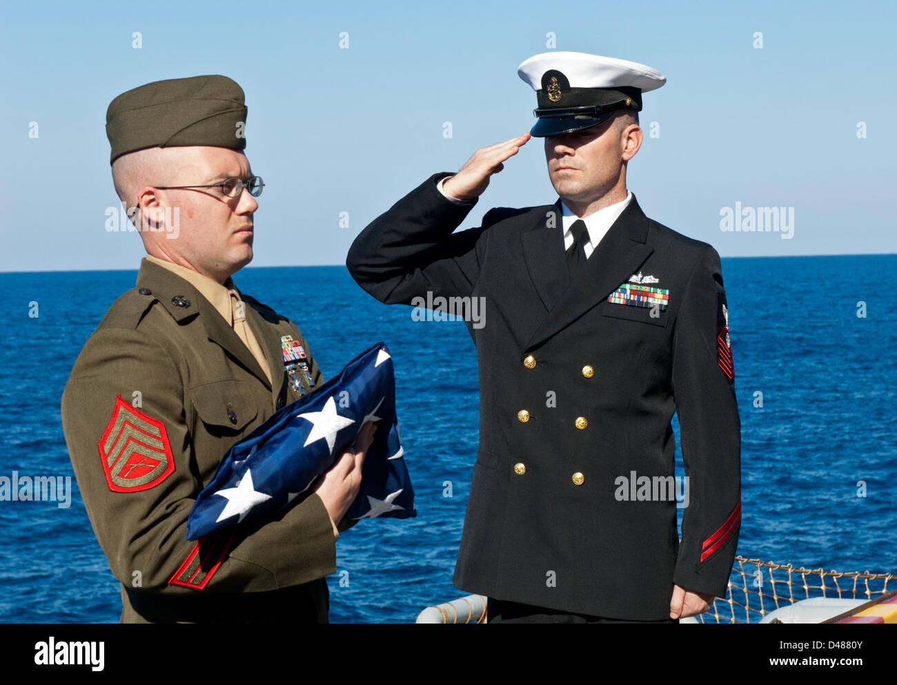 A U.S. Navy sailor salutes the flag during a burial at sea ceremony in ...
