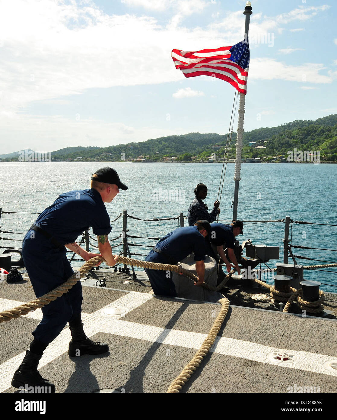 Sailors aboard the USS Underwood handle a mooring line, ensuring secure ...