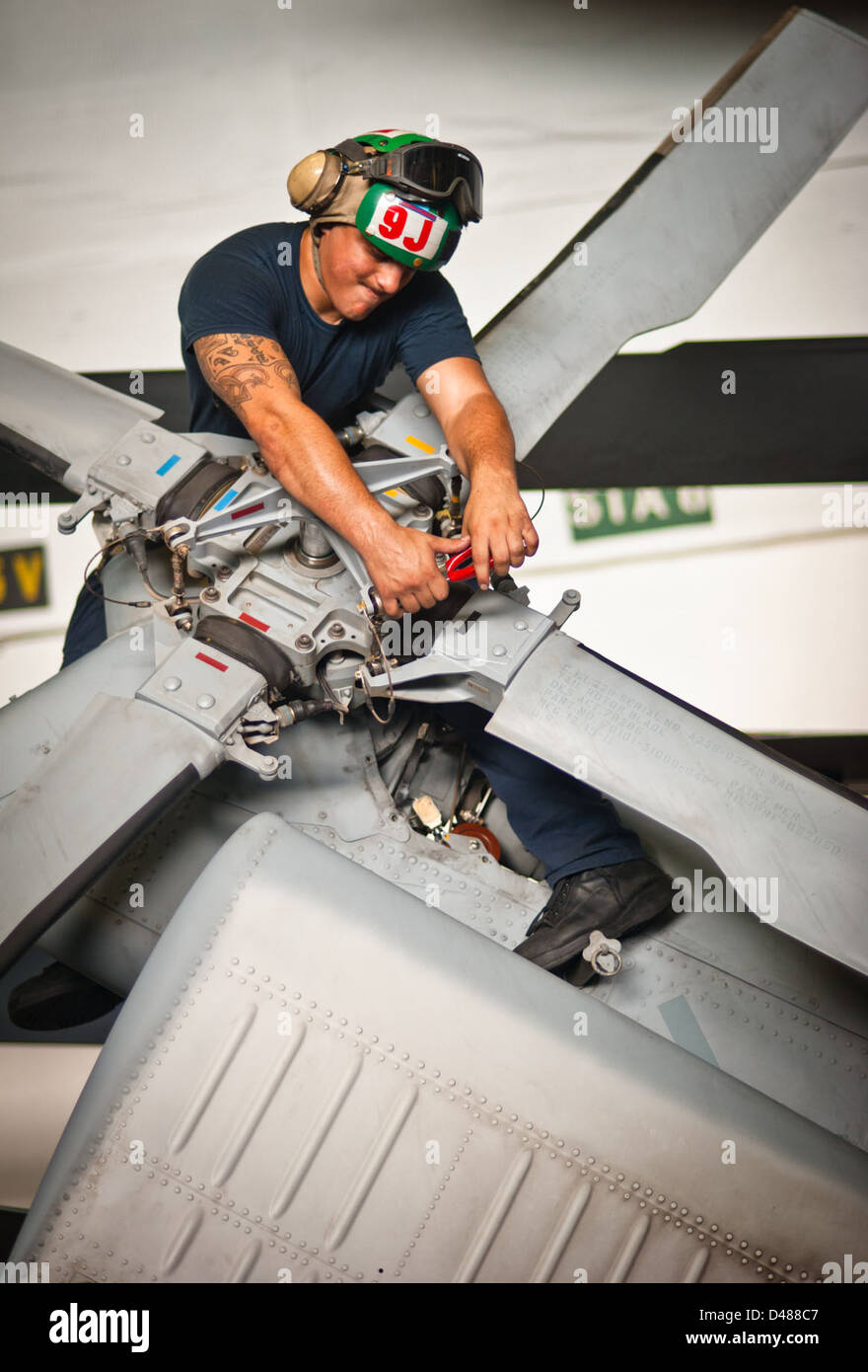 A Sailor performs maintenance on the tail rotor of an MH-60S helicopter ...