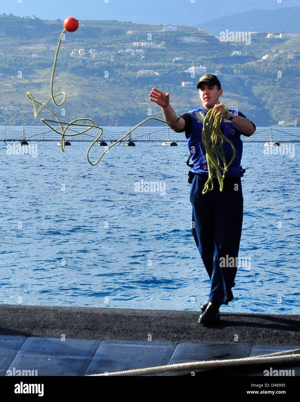 A Sailor throws a messenger line to facilitate communications and ...