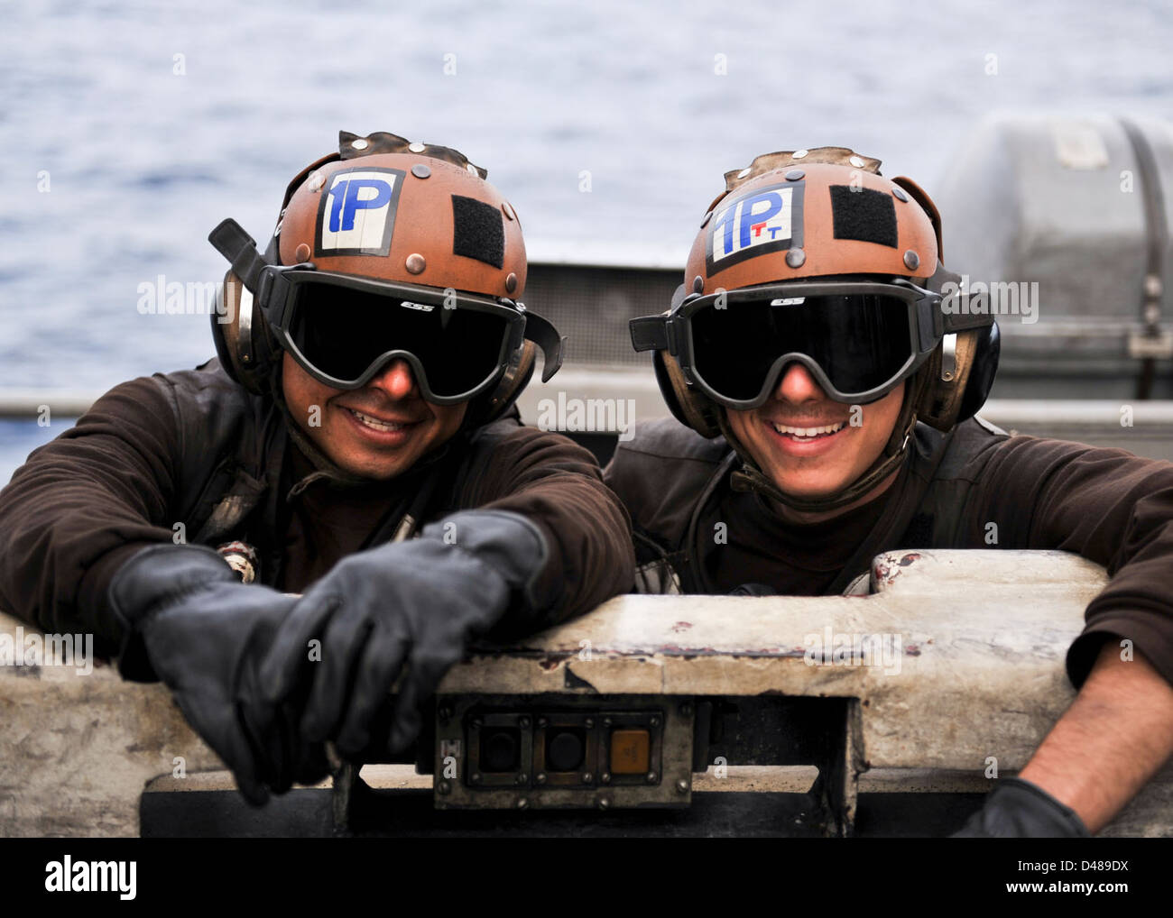 Sailors stand by the edge of the flight deck aboard a U.S. Navy ship ...