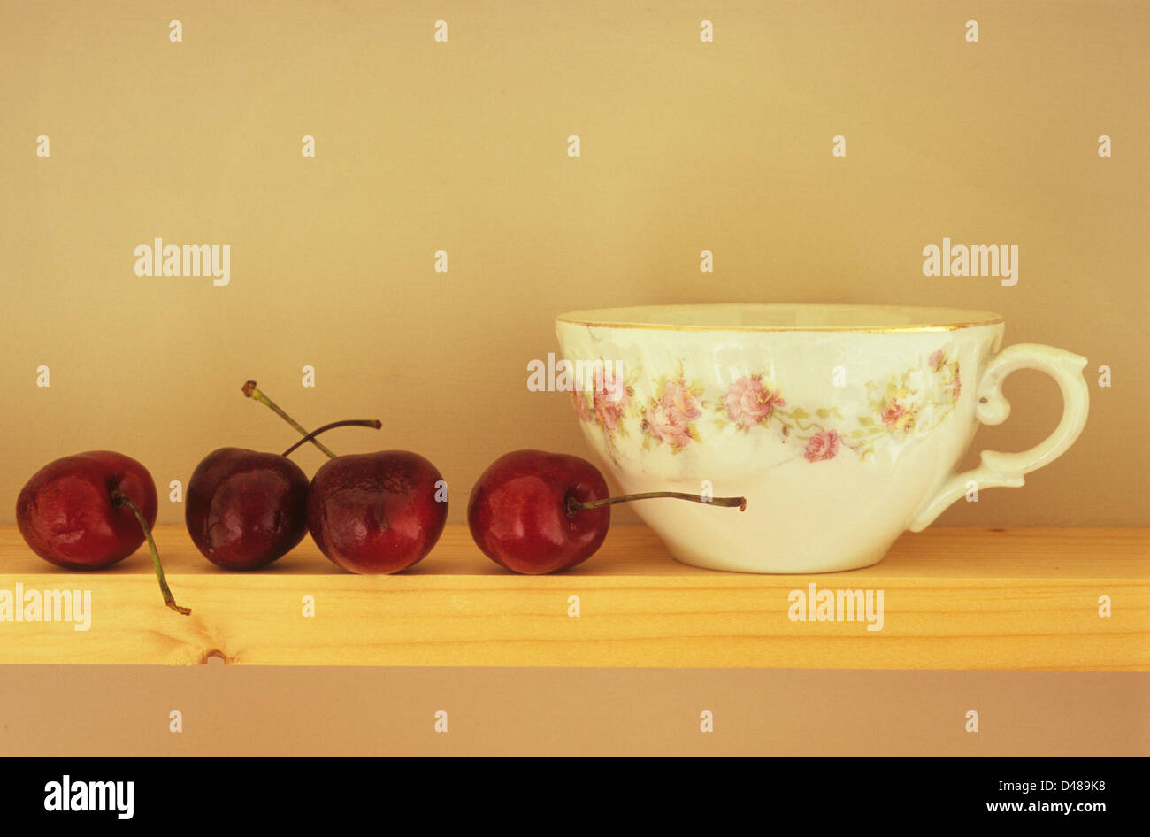 Eye-level view of narrow wooden shelf with four dark red cherries with ...