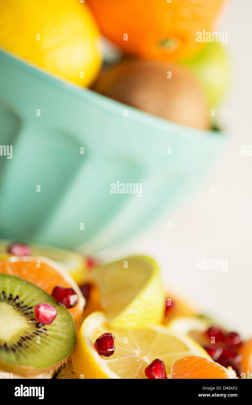A bowl of citrus fruits, surrounded by fruit segments and slices on a ...