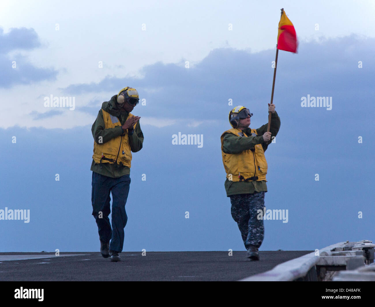 Sailors aboard a Navy ship wave a guide flag, a signal used for ...
