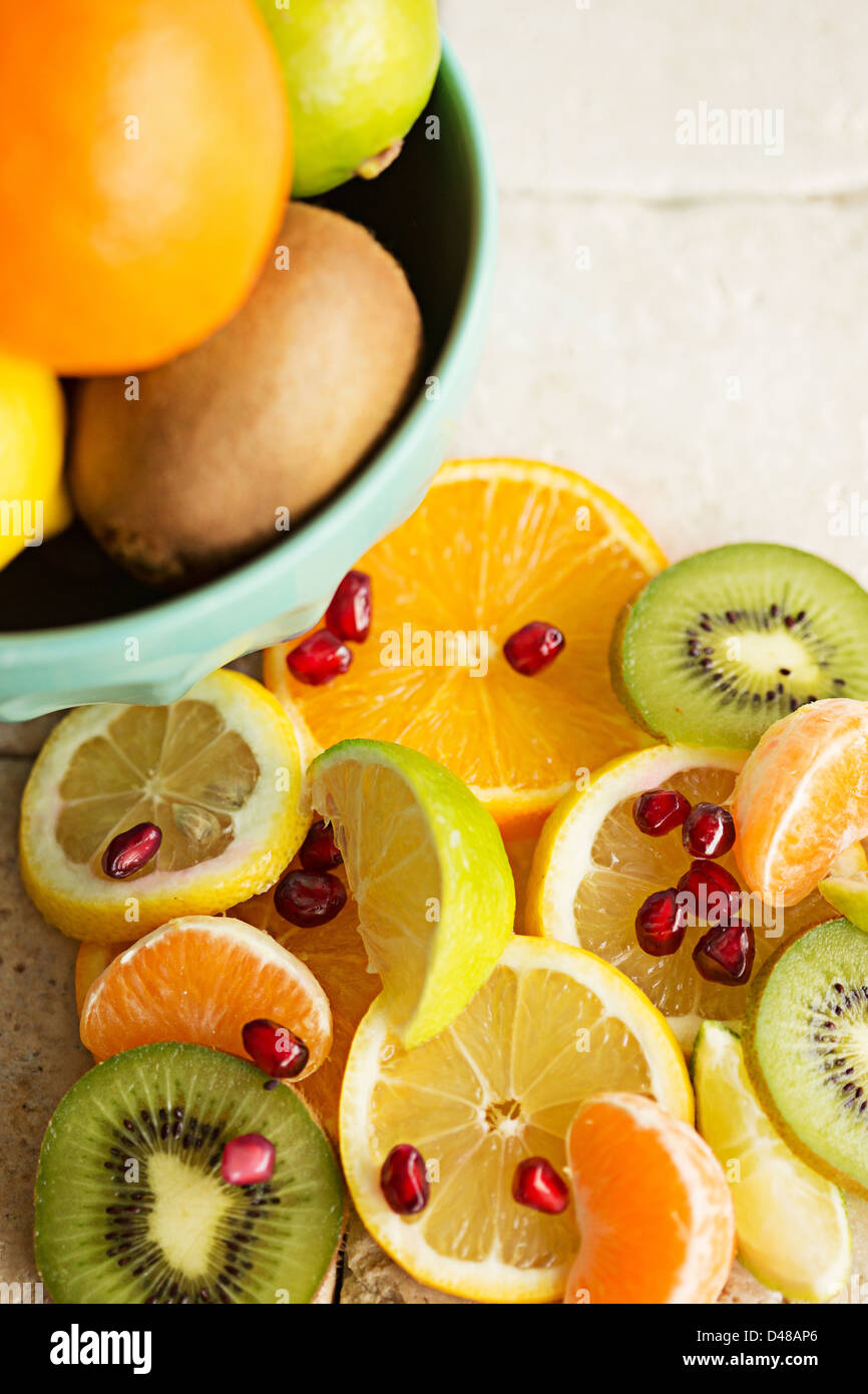 A bowl of citrus fruits, surrounded by fruit segments and slices on a ...