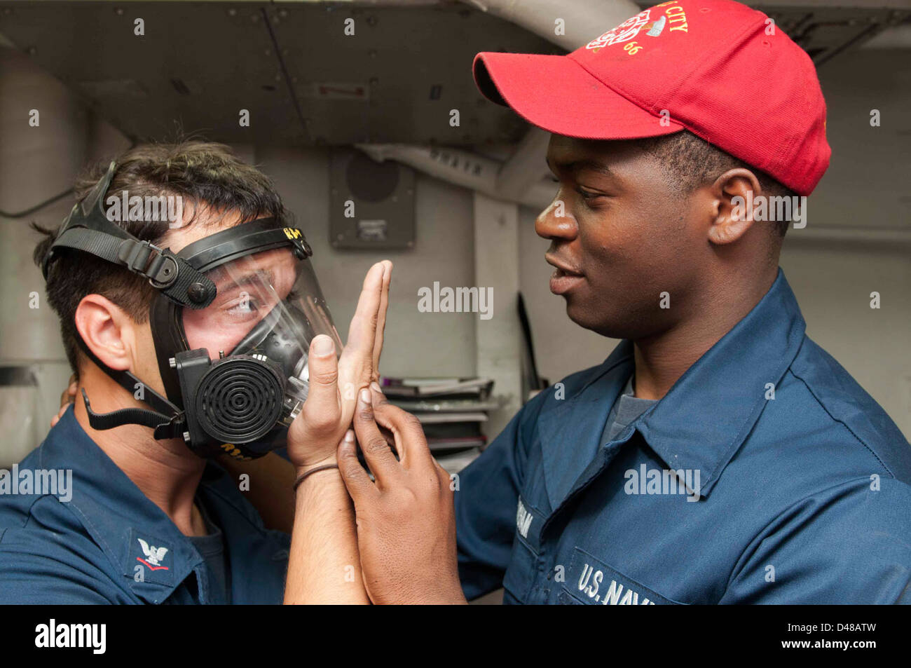 A Sailor tests the seal of his gas mask as part of routine military ...