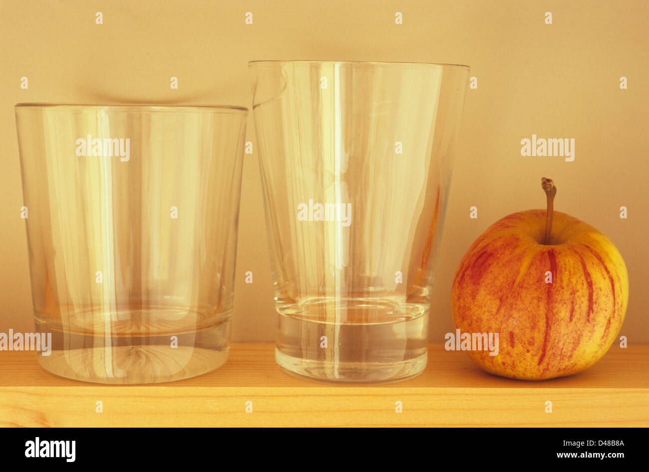 Eye-level view of narrow wooden shelf with two empty glasses and red ...