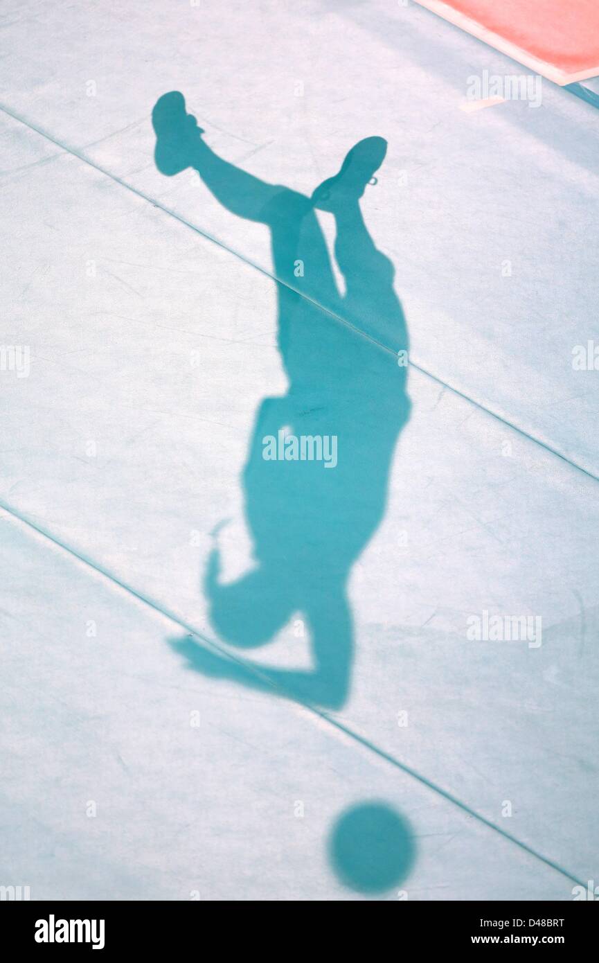 The shadow of a volleyball player appears on the floor of the sports ...