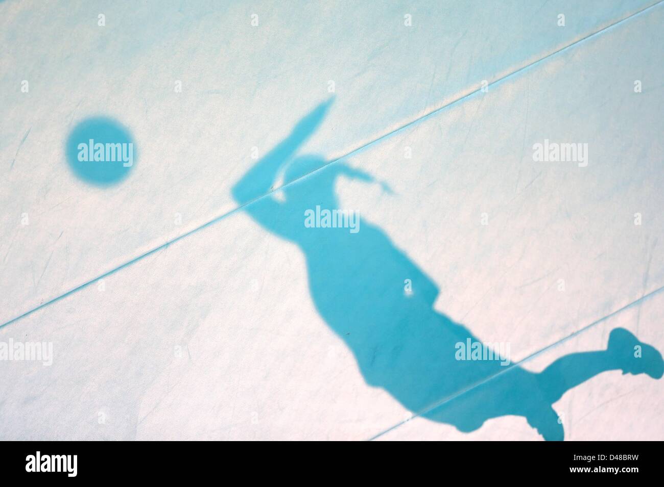 The shadow of a volleyball player appears on the floor of the sports ...