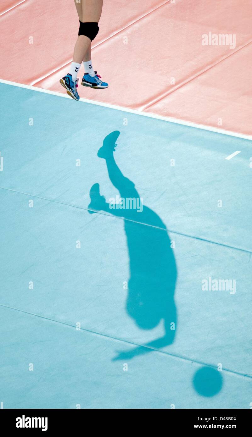 The shadow of a volleyball player appears on the floor of the sports ...
