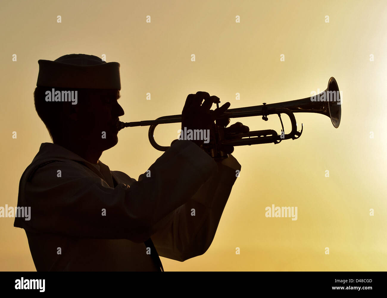 A Sailor plays 'Taps' at sunset in Pearl Harbor, a somber tribute to ...