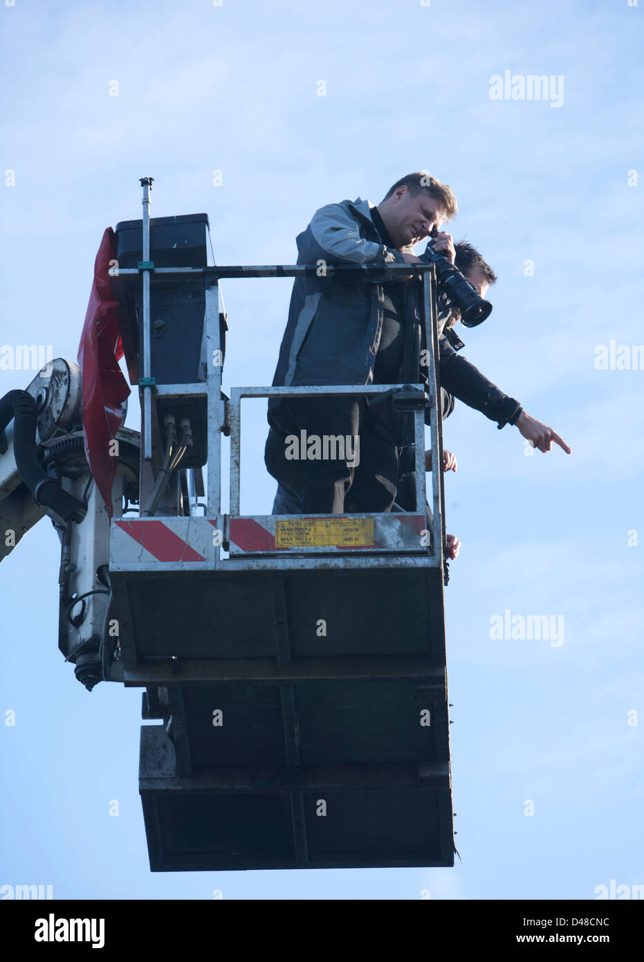 Three men in a cherry picker elevated with a blue sky background Stock ...