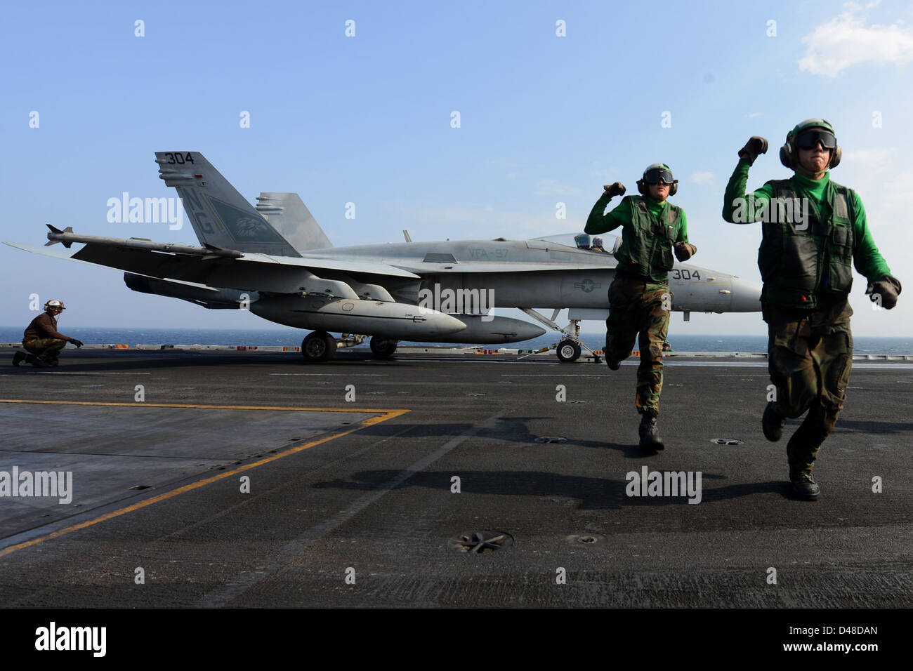Sailors aboard a U.S. Navy ship maneuver around aircraft in the Arabian ...