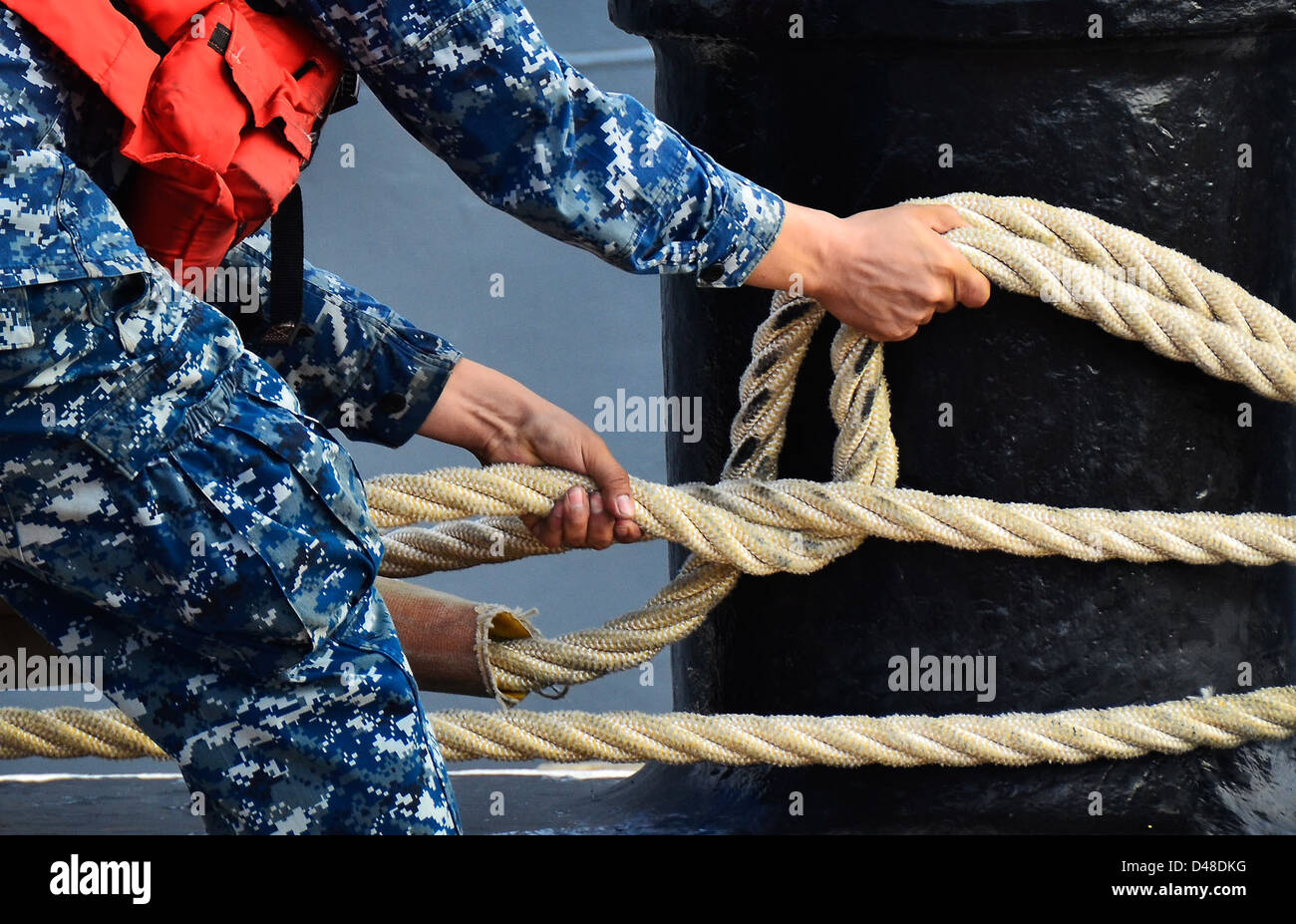 A Sailor handles mooring lines aboard a U.S. Navy ship at Pearl Harbor ...