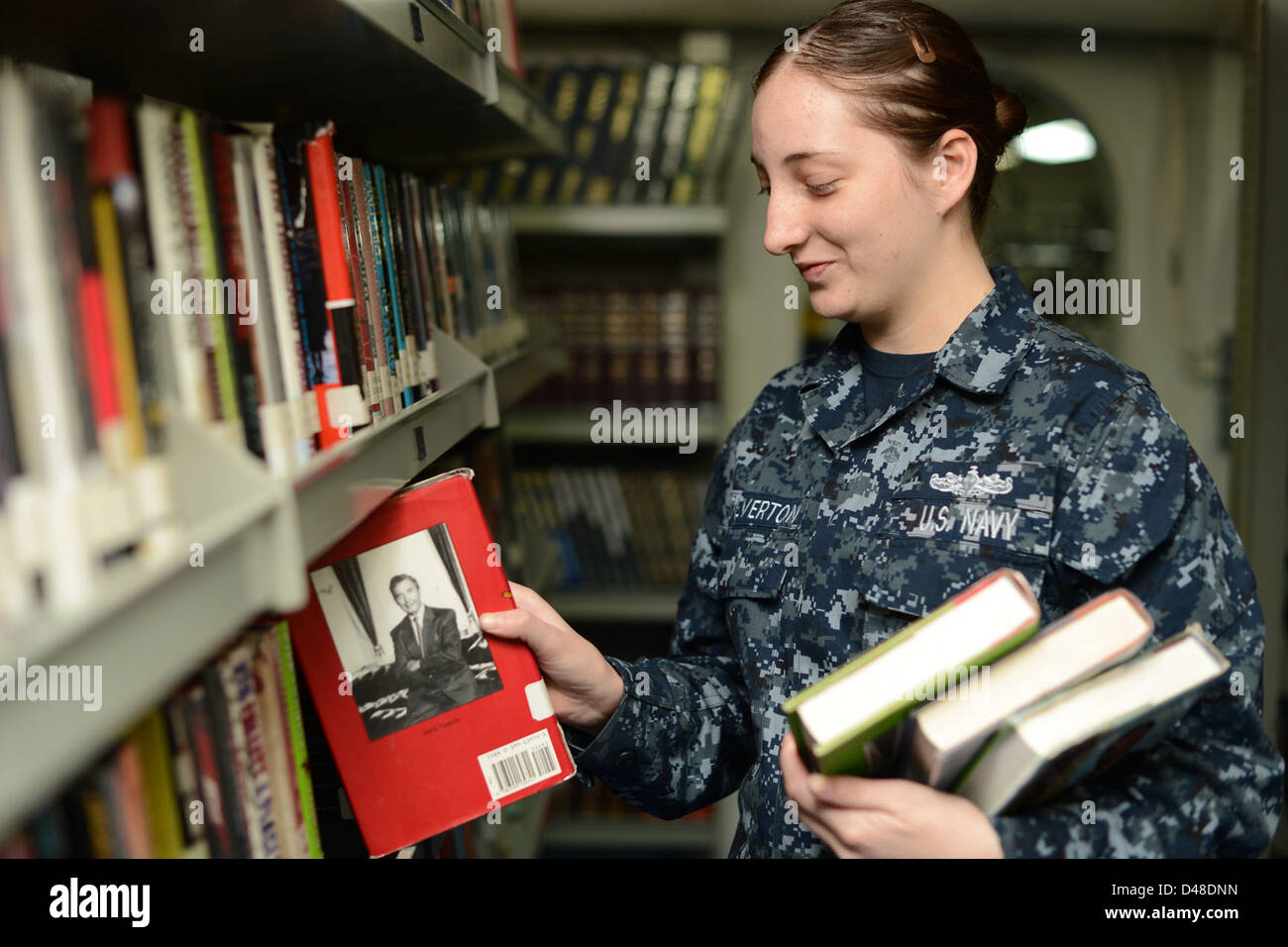 A Sailor sorts books in the ship's library Stock Photo - Alamy