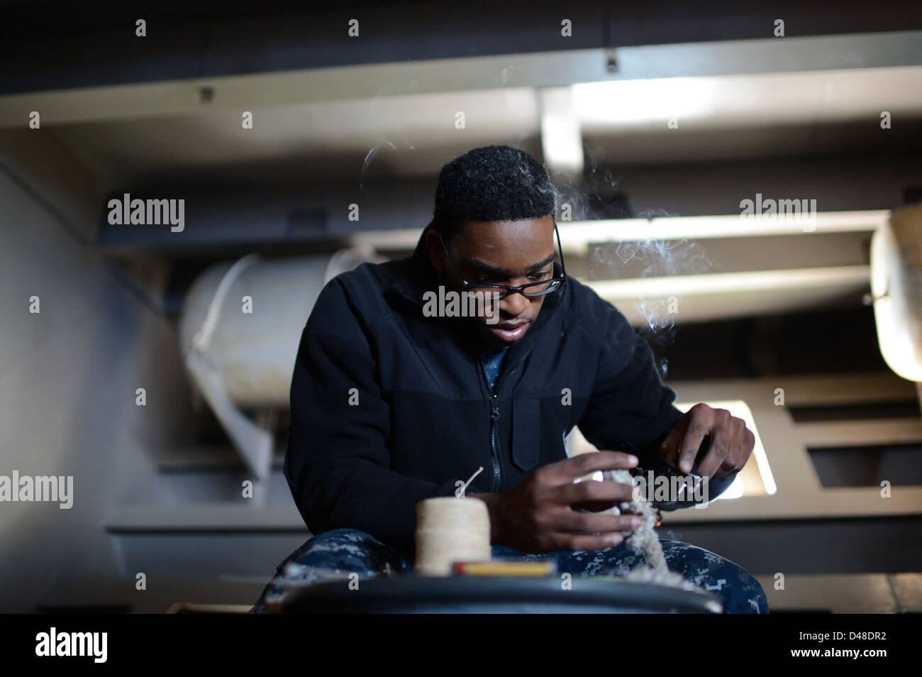 A Sailor repairs a messenger line aboard a U.S. Navy ship, ensuring ...