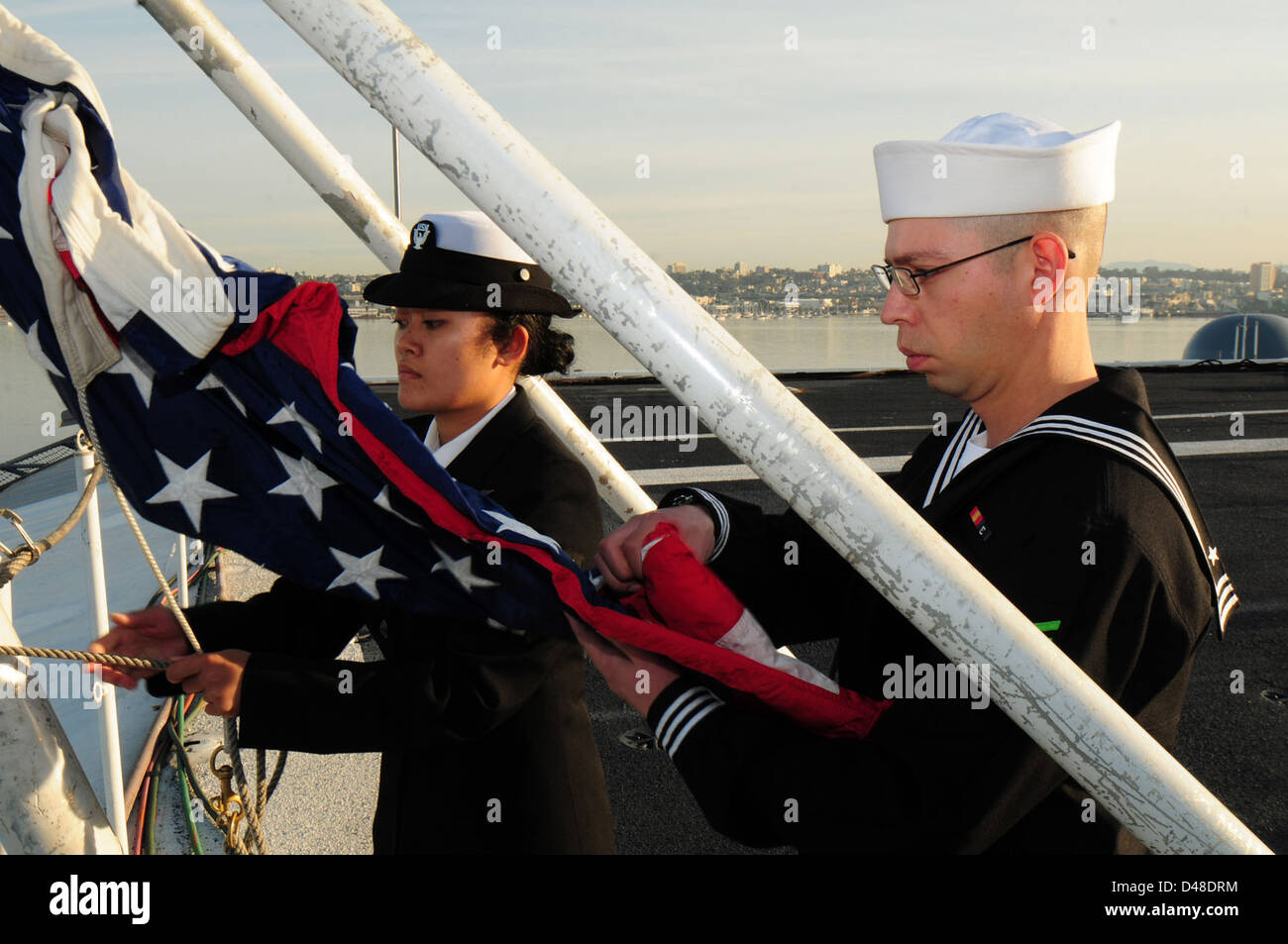 Sailors aboard a U.S. Navy ship raise the national ensign during ...
