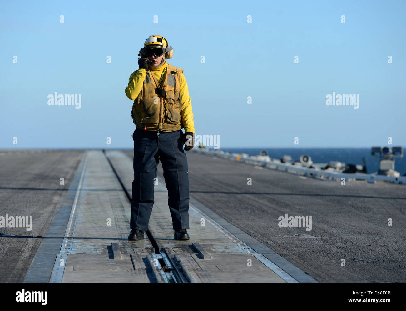 A U.S. Navy Sailor performs duties on the flight deck of a ship at sea ...