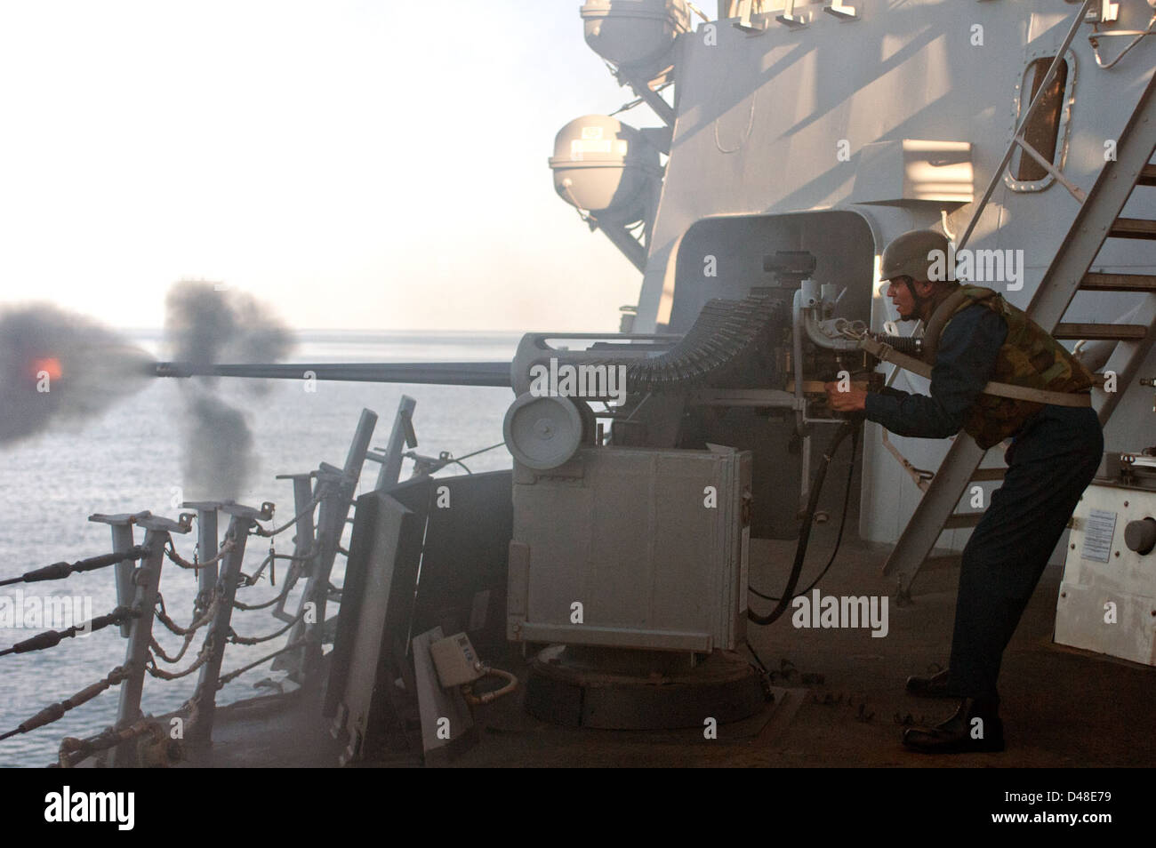 A U.S. Navy Sailor fires a 25mm gun as part of training exercises in ...
