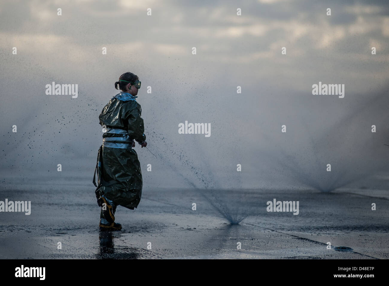 A Sailor performs a countermeasure washdown aboard a Navy vessel in the ...