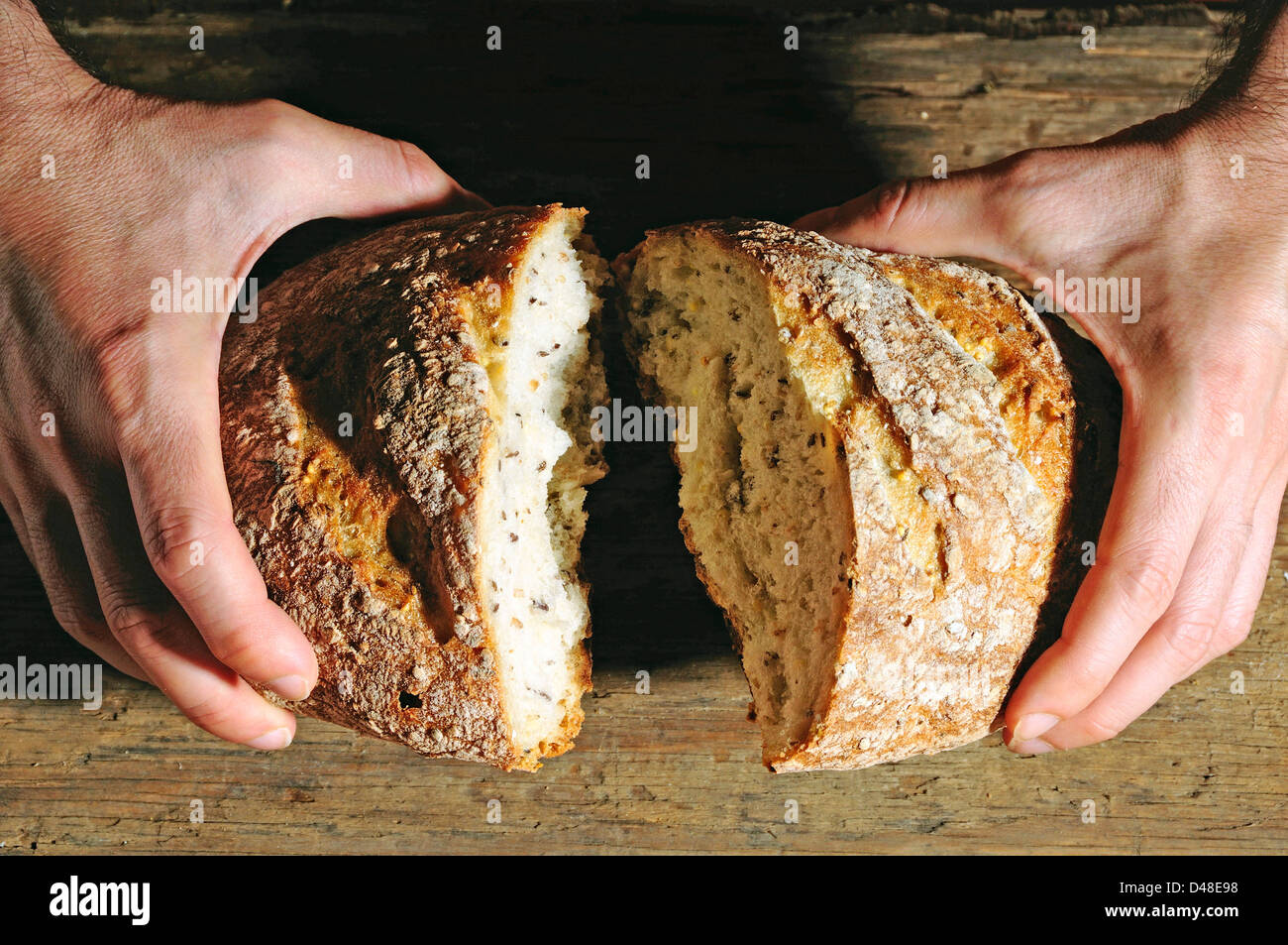 man breaking apart a loaf of bread, religious concept Stock Photo - Alamy
