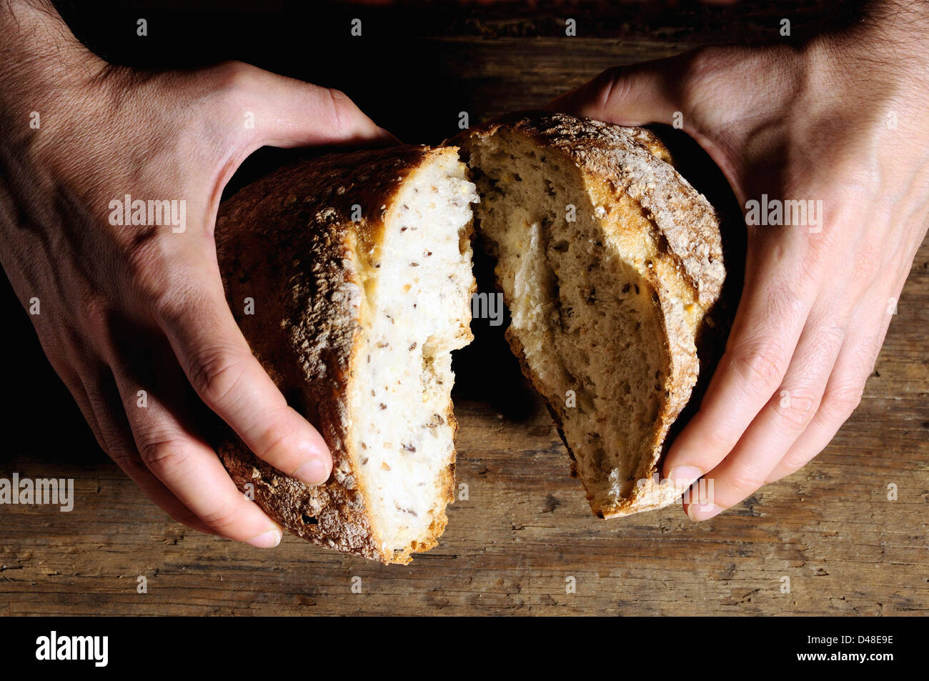 man breaking apart a loaf of bread, religious concept Stock Photo - Alamy