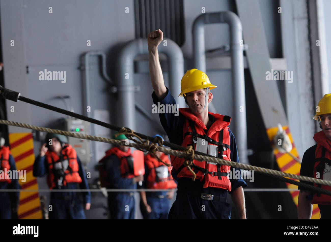 A U.S. Navy sailor supervises the onloading of ammunition aboard a Navy ...