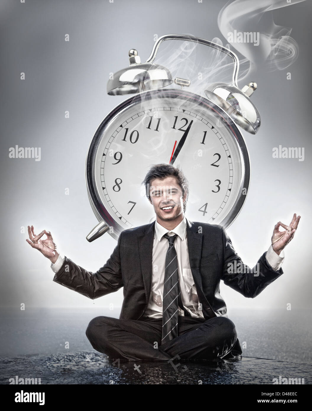 Businessman meditating in front of alarm clock Stock Photo - Alamy