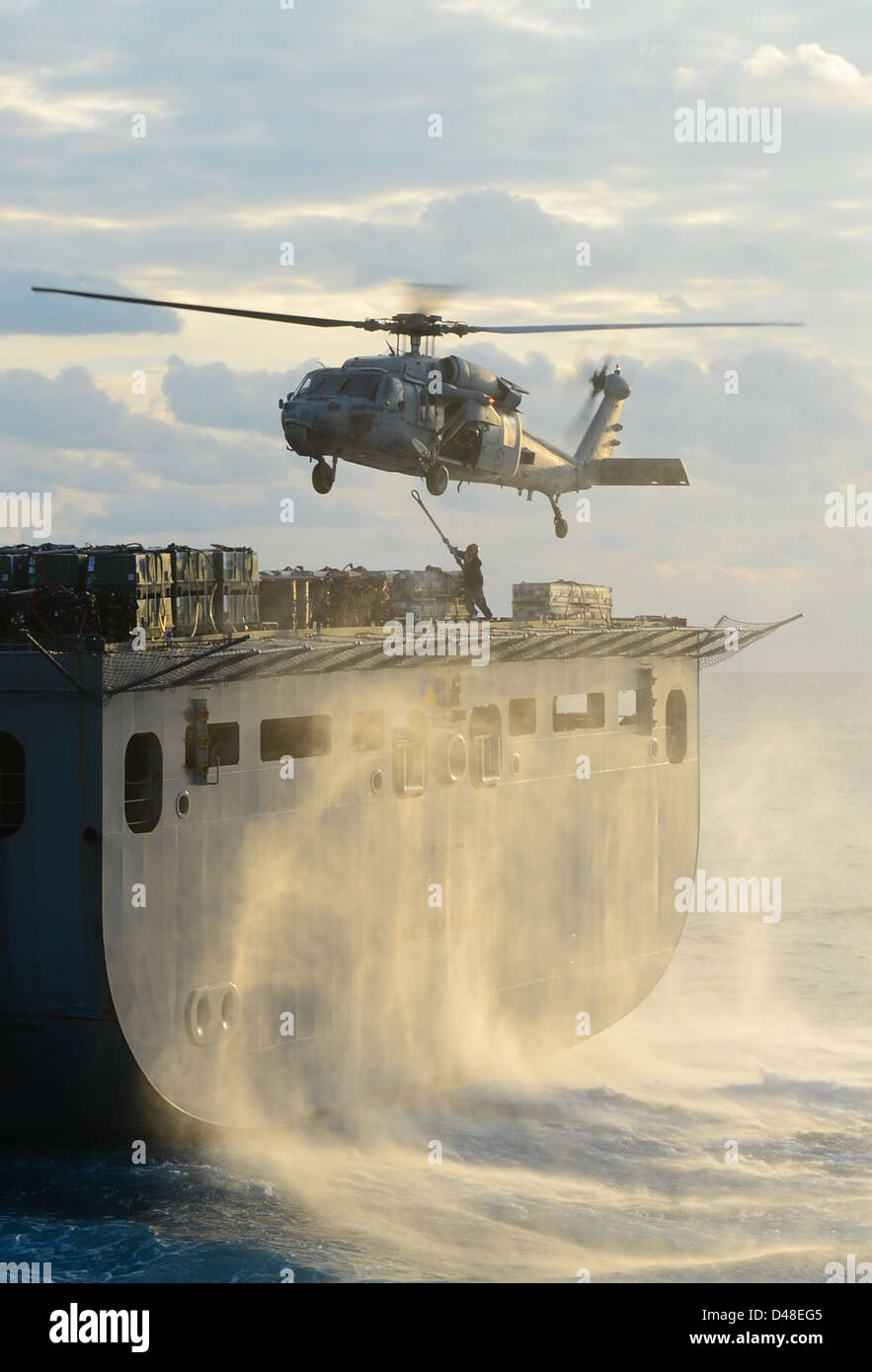 An MH-60S helicopter conducts a vertical replenishment operation ...