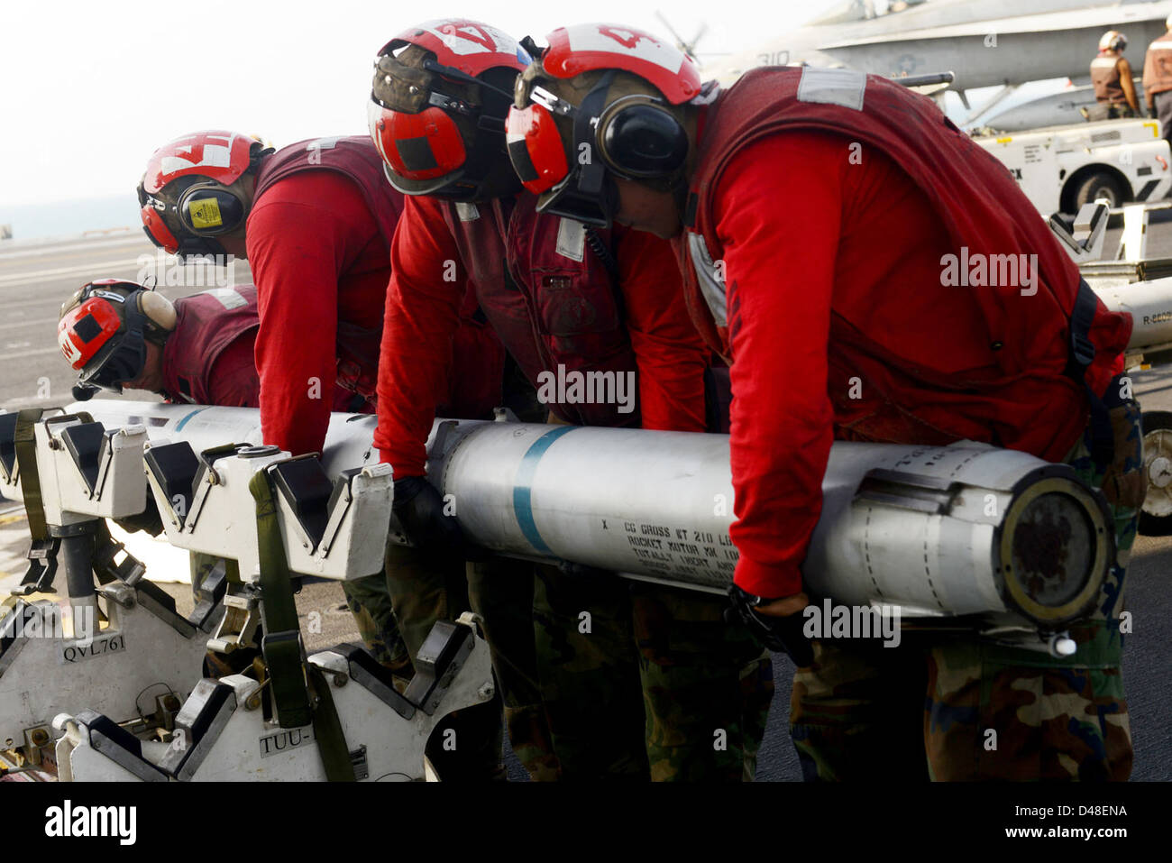 Sailors aboard a U.S. Navy ship carefully move ordnance at sea to ...