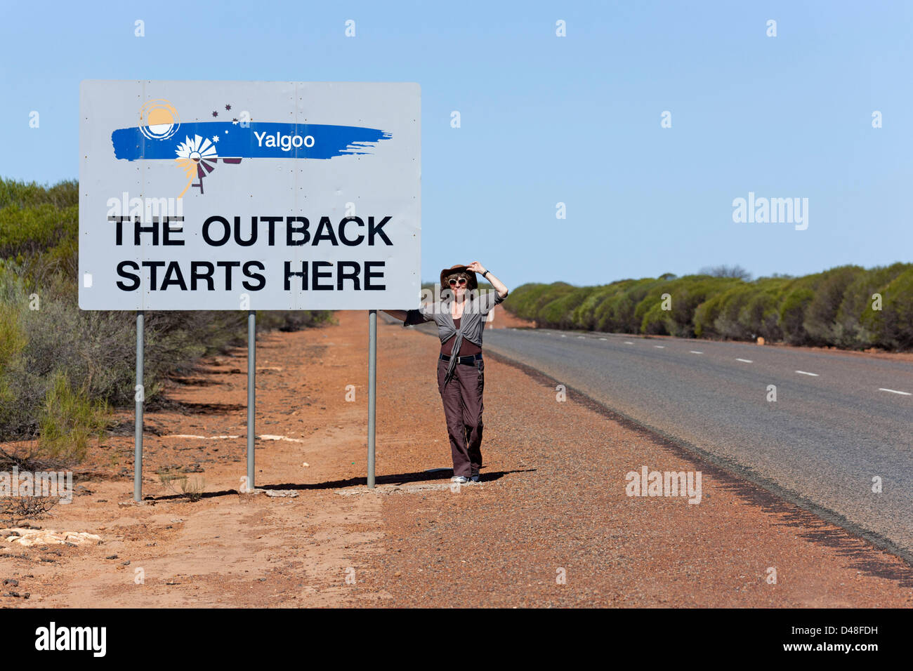 Woman standing alongside of a Outback road sign, Yalgoo Western ...