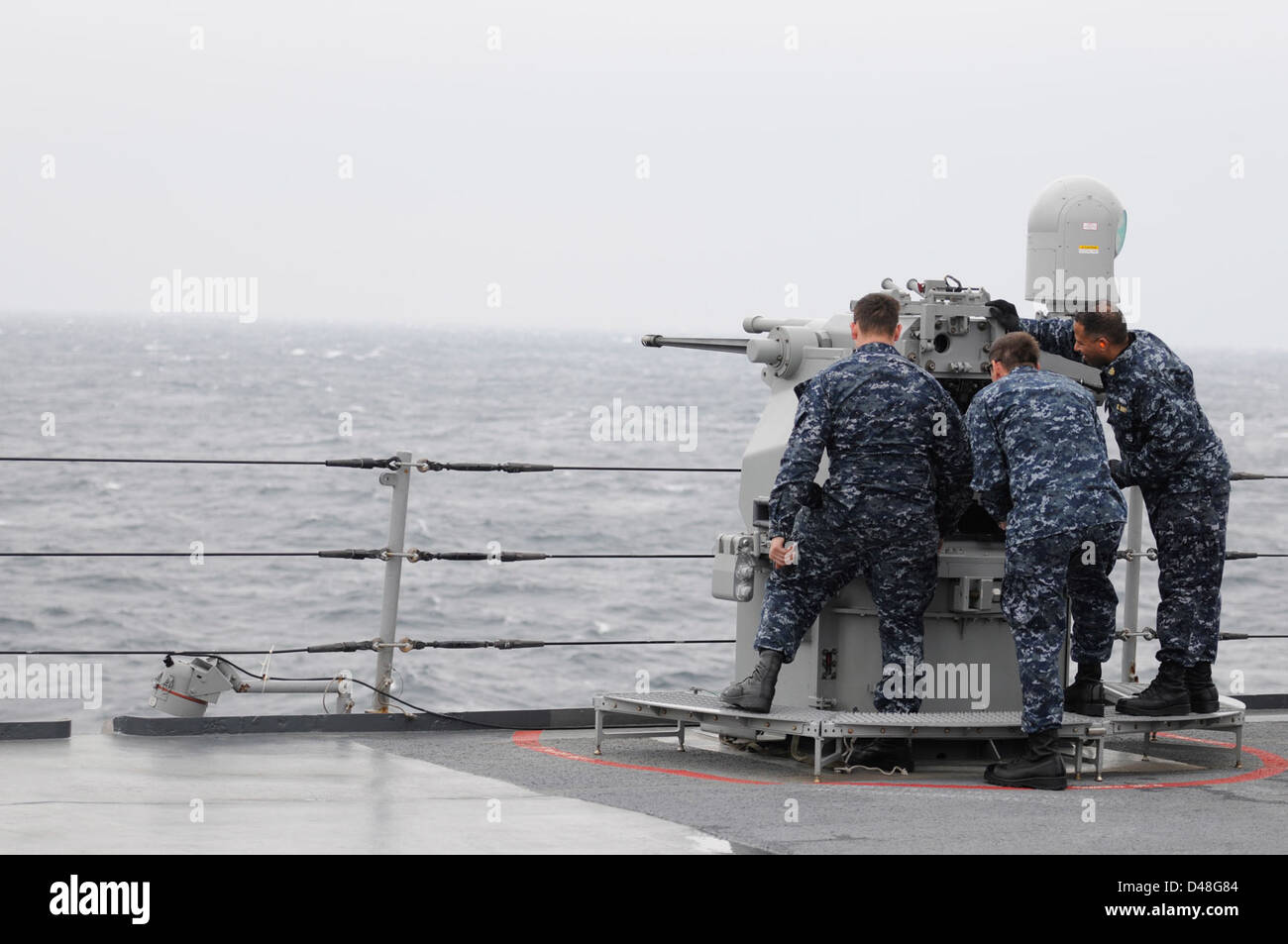 Sailors aboard a U.S. Navy ship prepare a 25mm gun for an upcoming ...