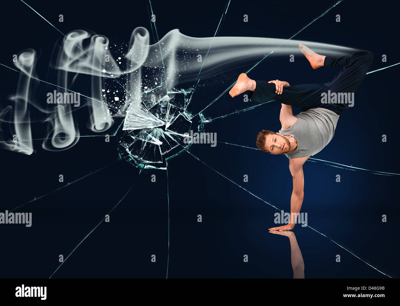 Martial arts expert doing hand stand against broken glass background ...