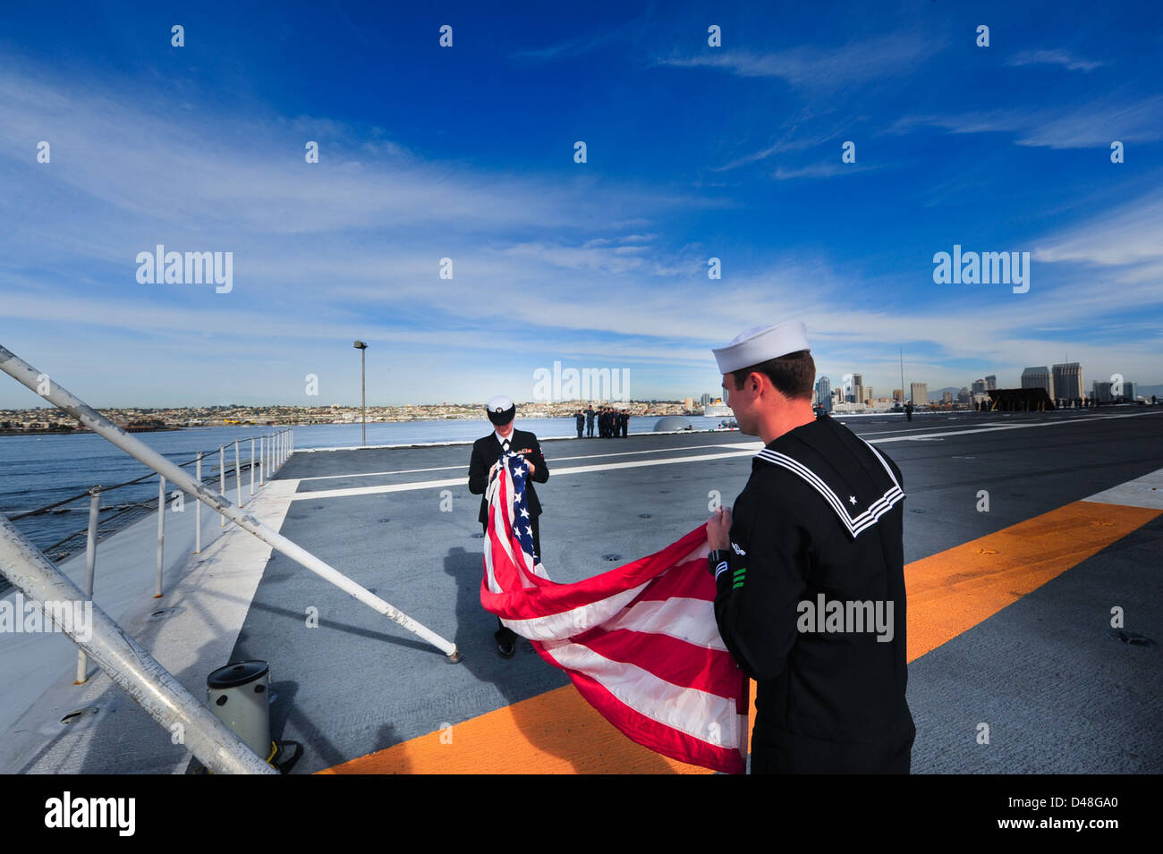 Sailors aboard the USS Carl Vinson fold the American flag during a ...