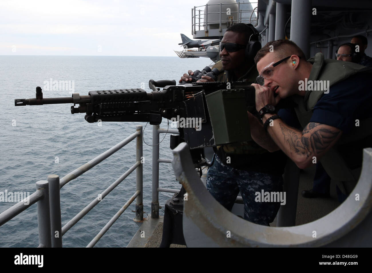 A U.S. Navy Sailor fires an M240B machine gun at sea during an exercise ...