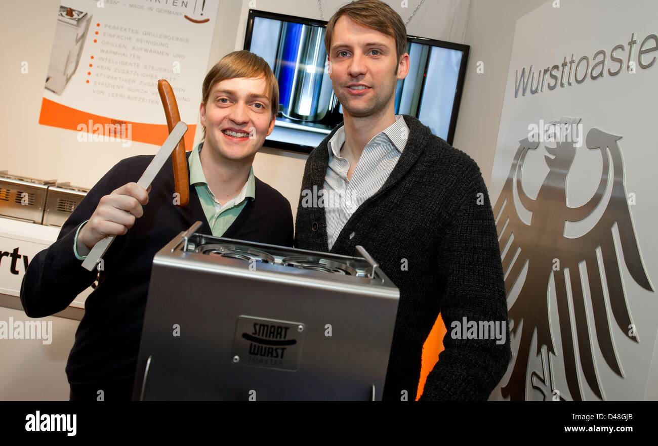 Felix Rennies (L) and Marco Bruns present a sausage toaster at trade ...