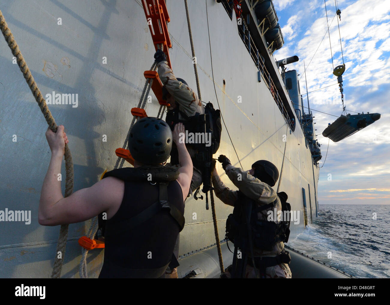 Sailors board a rigid-hull inflatable boat (RHIB) from USS Carter Hall ...
