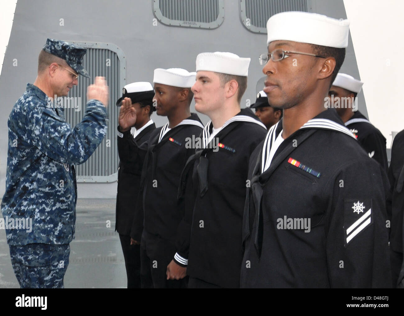 A U.S. Navy officer inspects the uniform of a service member as part of ...