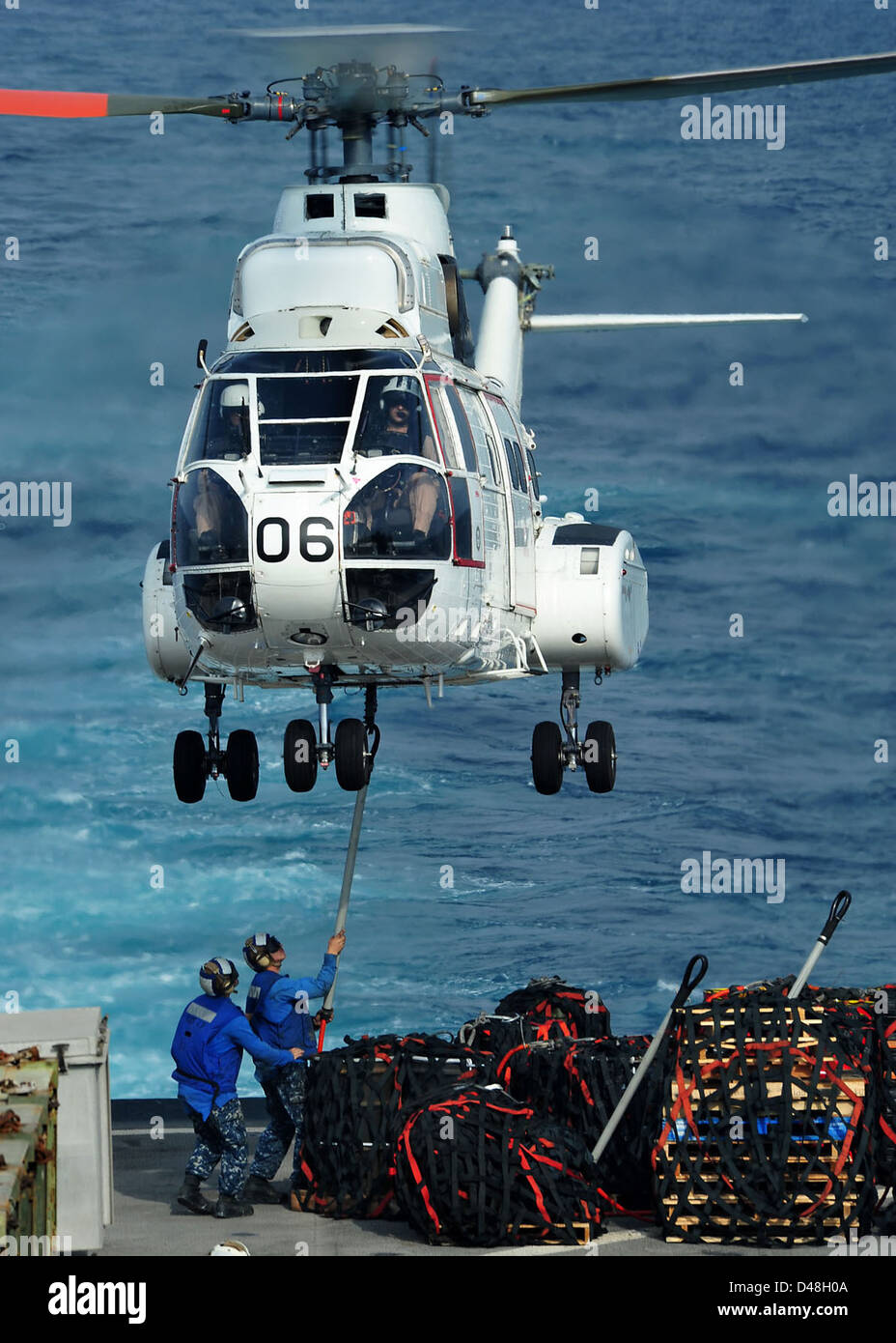 Sailors aboard the USS Rushmore hook cargo to an AS 332 helicopter ...