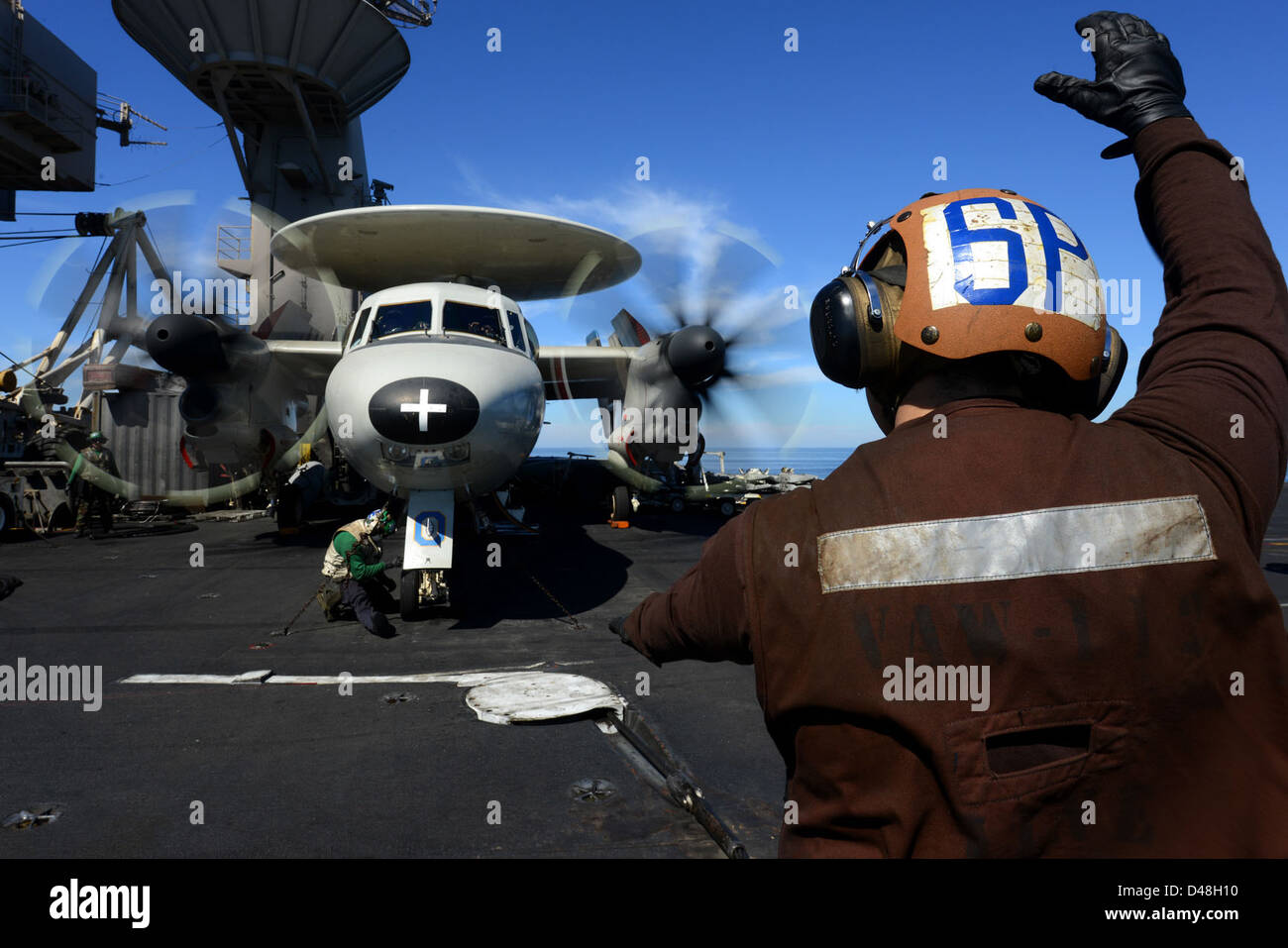 A Sailor signals pilots aboard an E-2C Hawkeye in the U.S. 5th Fleet ...