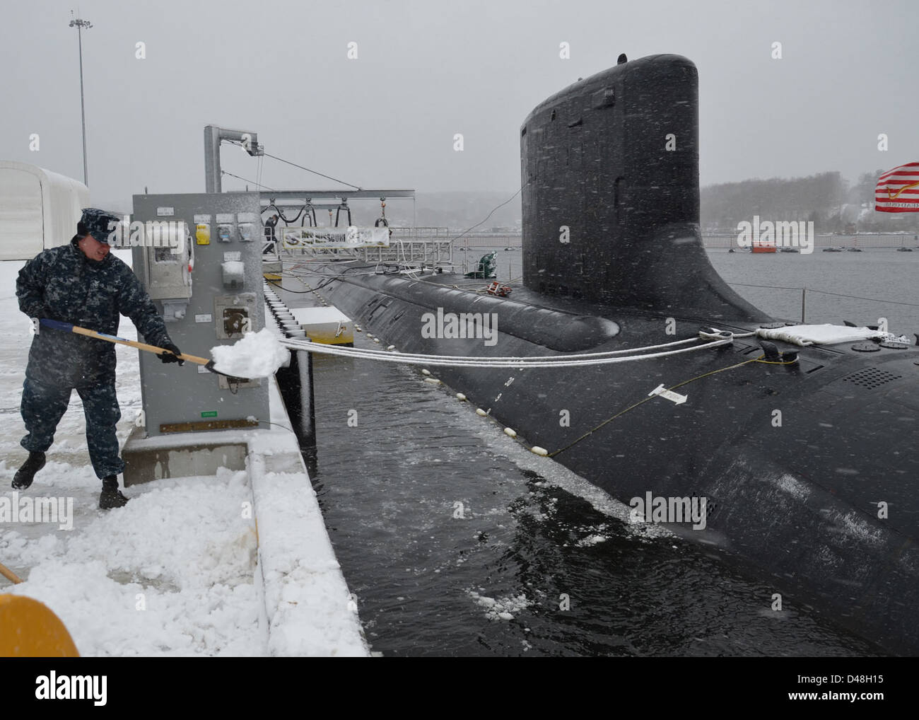 A Sailor shovels snow near the USS Missouri in Groton, Connecticut ...