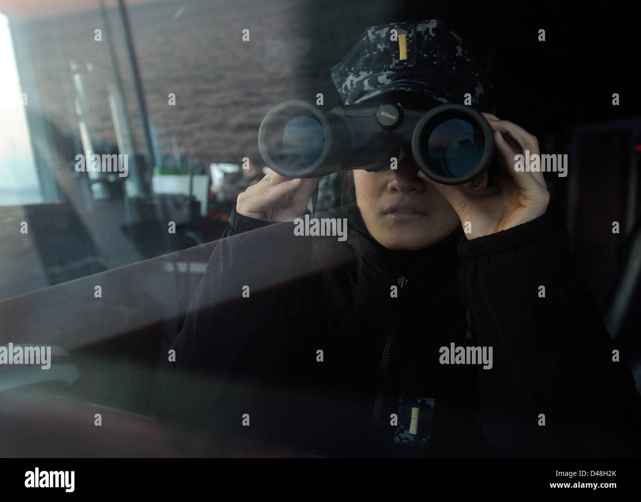 An officer stands watch on the bridge of the USS Blue Ridge, overseeing ...