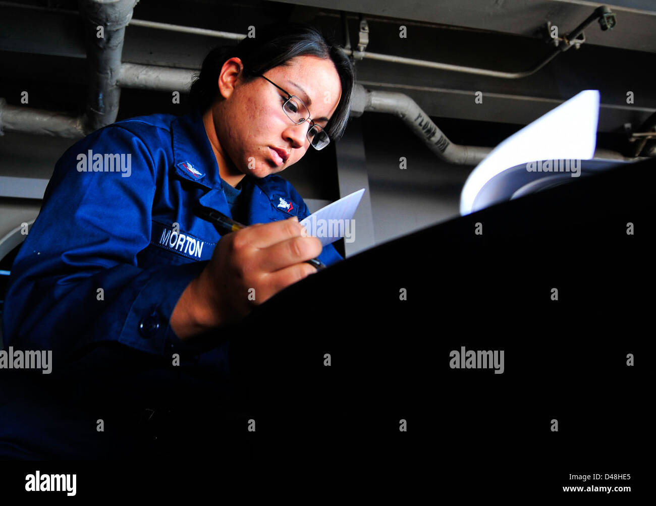 A Sailor aboard a U.S. Navy vessel studies for her advancement exam in ...