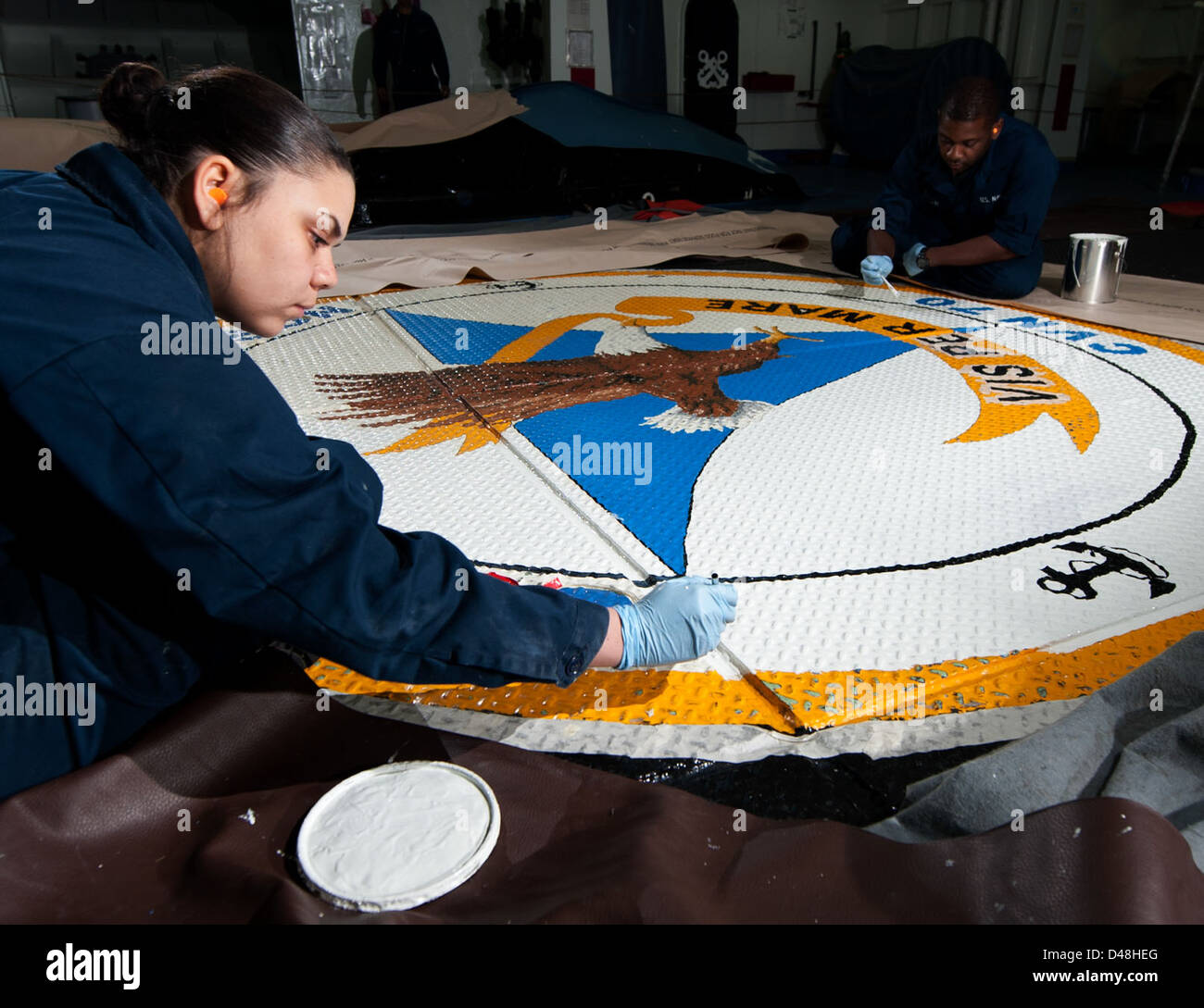 Sailors paint the USS Carl Vinson's ship crest aboard the aircraft ...