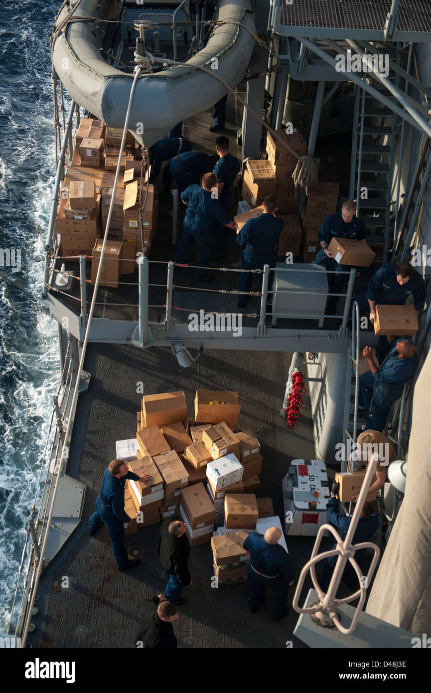 U.S. Navy sailors move supplies aboard the USS Mobile Bay, stationed in ...